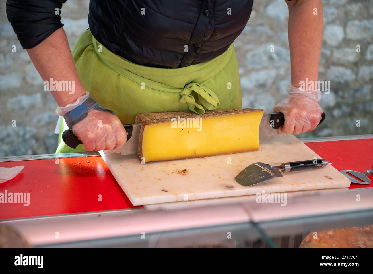 Cutting french yellow cheese Comte in pieces, varieties unpasteurised ...