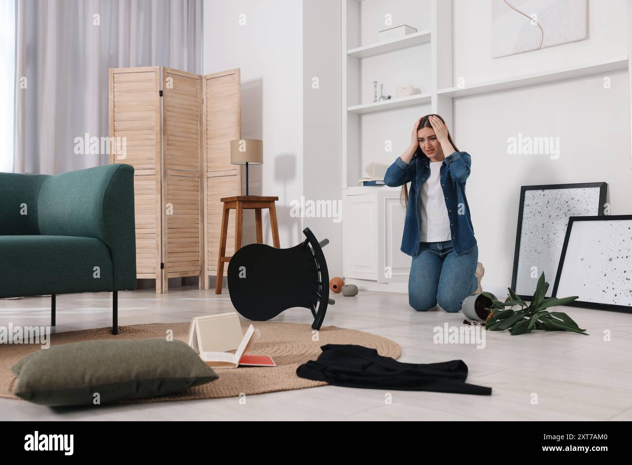Desperate woman sitting on floor in messy living room after robbery ...