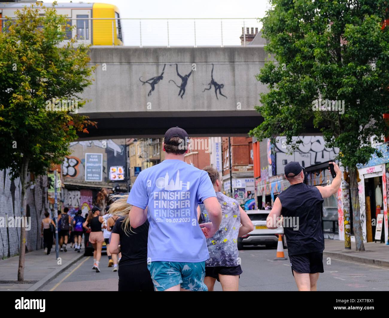 Runners pass under the Banksy artwork of three monkeys painted onto a ...