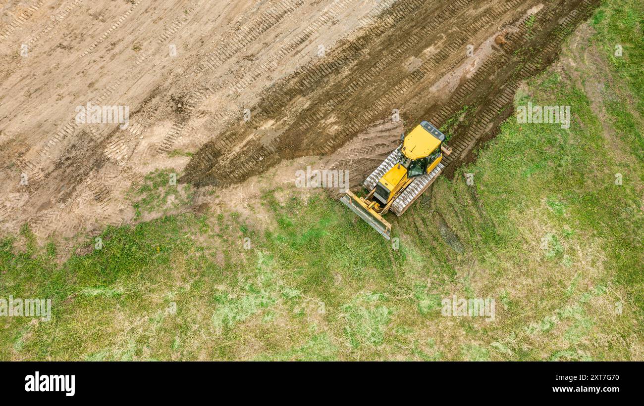 yellow bulldozer is moving and flattening soil. earthworks on ...