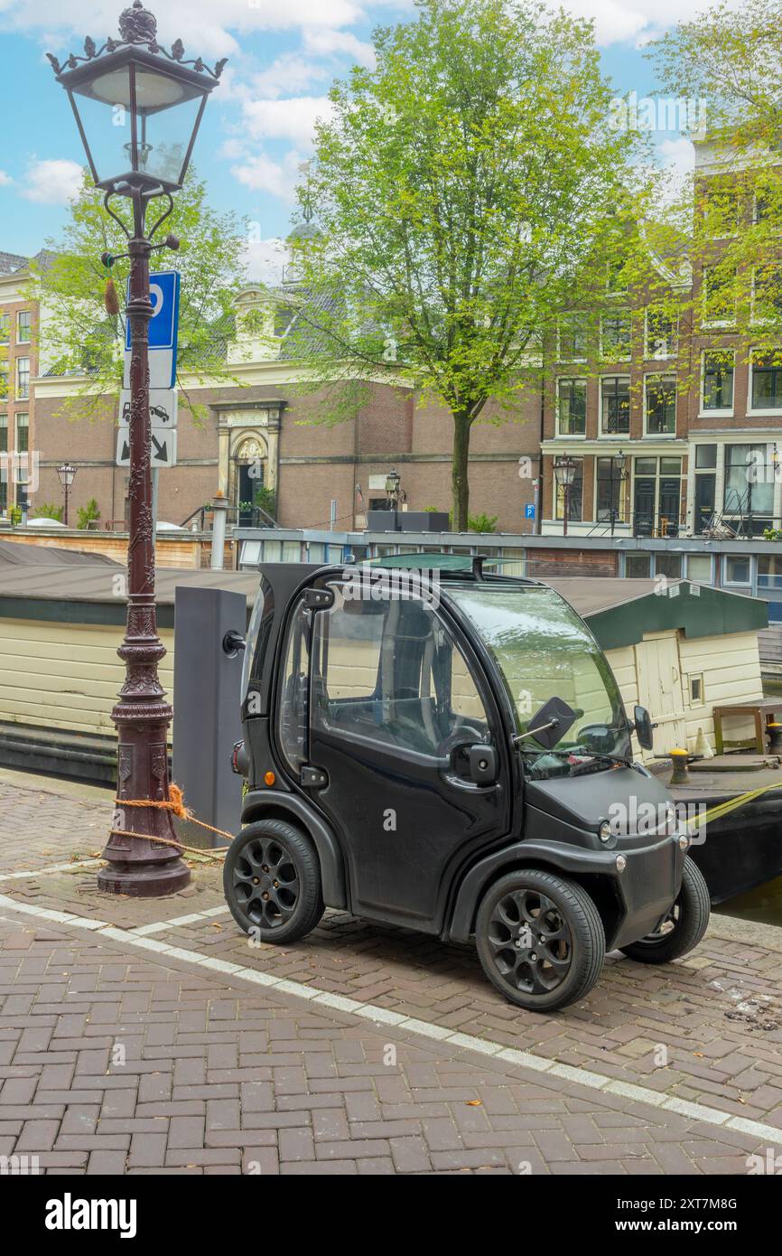Netherlands. Summer day in Amsterdam. Electric mini-car is tied to a ...