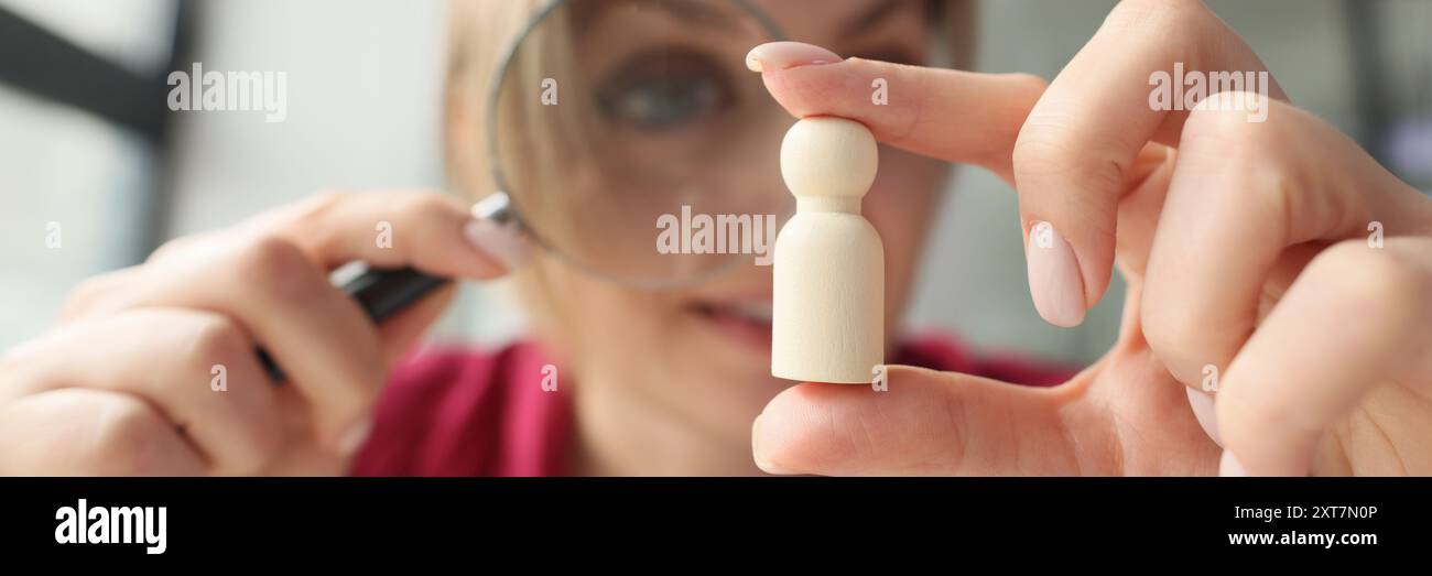 Woman looking at wooden person figure through magnifying glass Stock ...