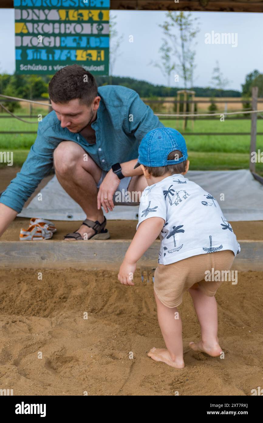Dad and son in the sandbox at the archaeological park excavating with a ...