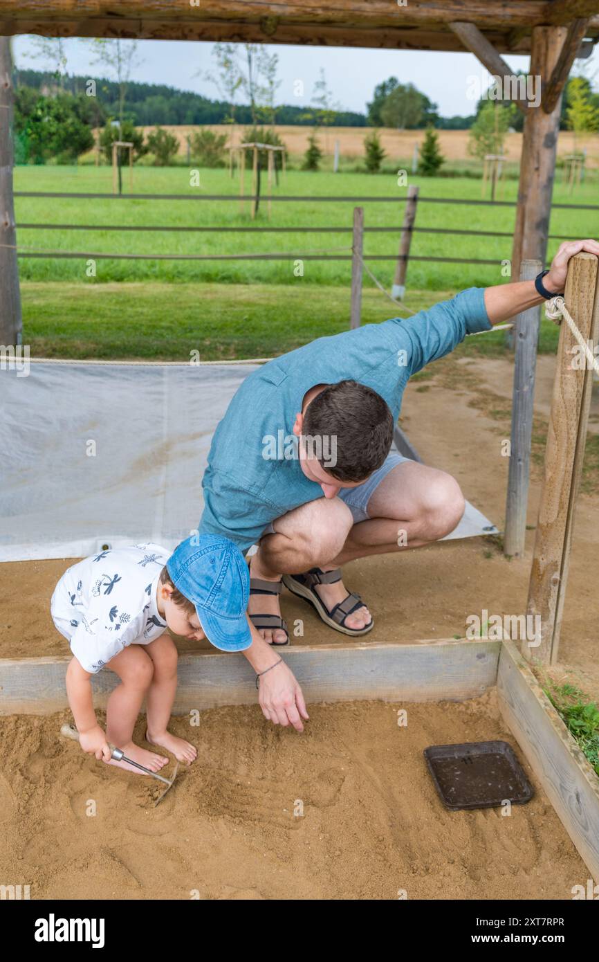 Dad and son in the sandbox at the archaeological park excavating with a ...