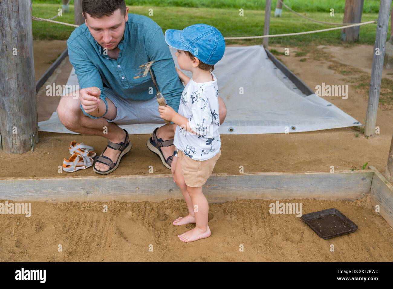 Dad and son in the sandbox at the archaeological park excavating with a ...