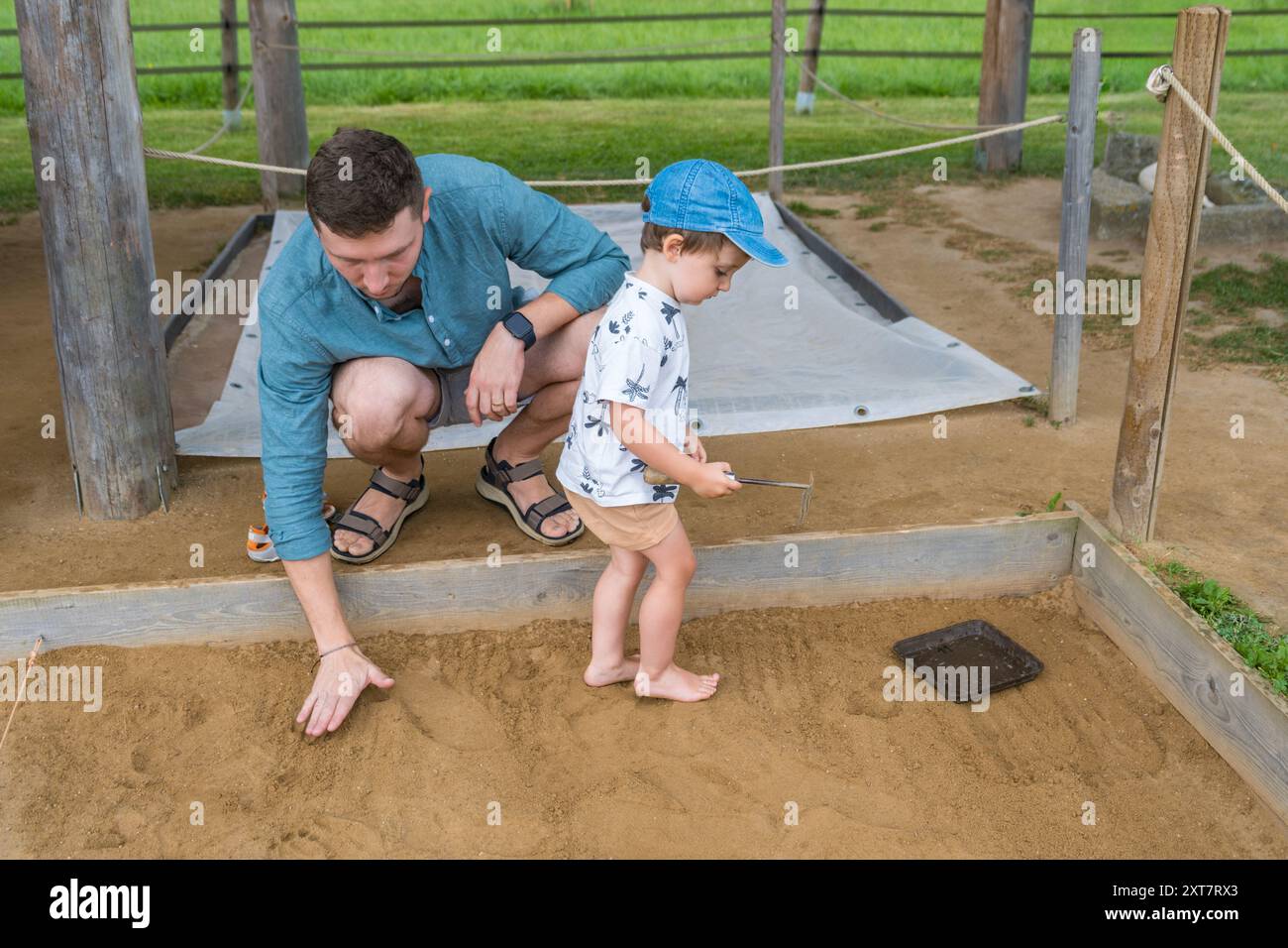 Dad and son in the sandbox at the archaeological park excavating with a ...