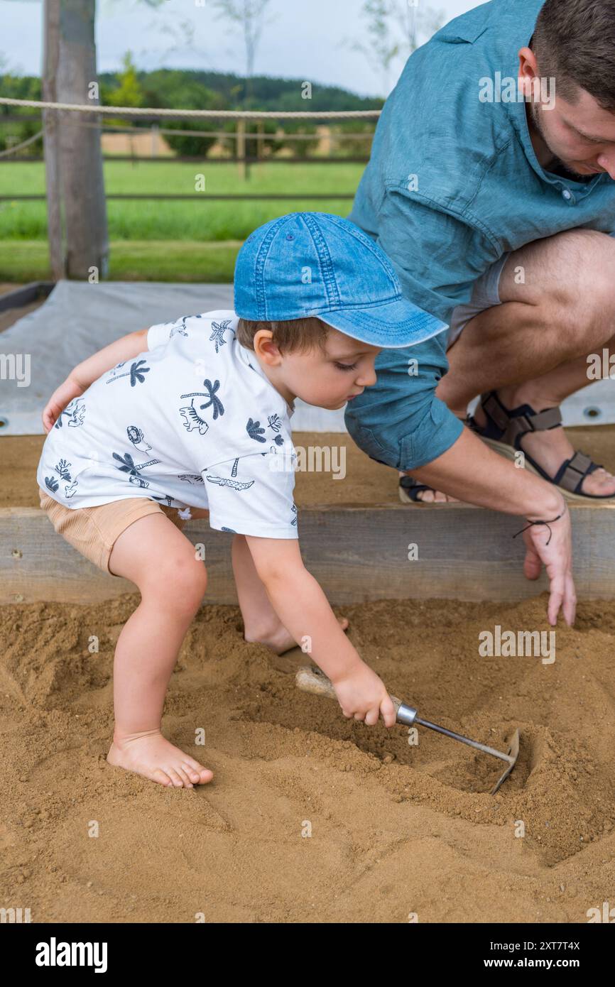 Dad and son in the sandbox at the archaeological park excavating with a ...