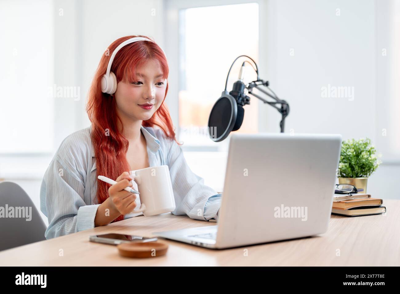 A confident and beautiful Asian female podcaster is working in her home ...