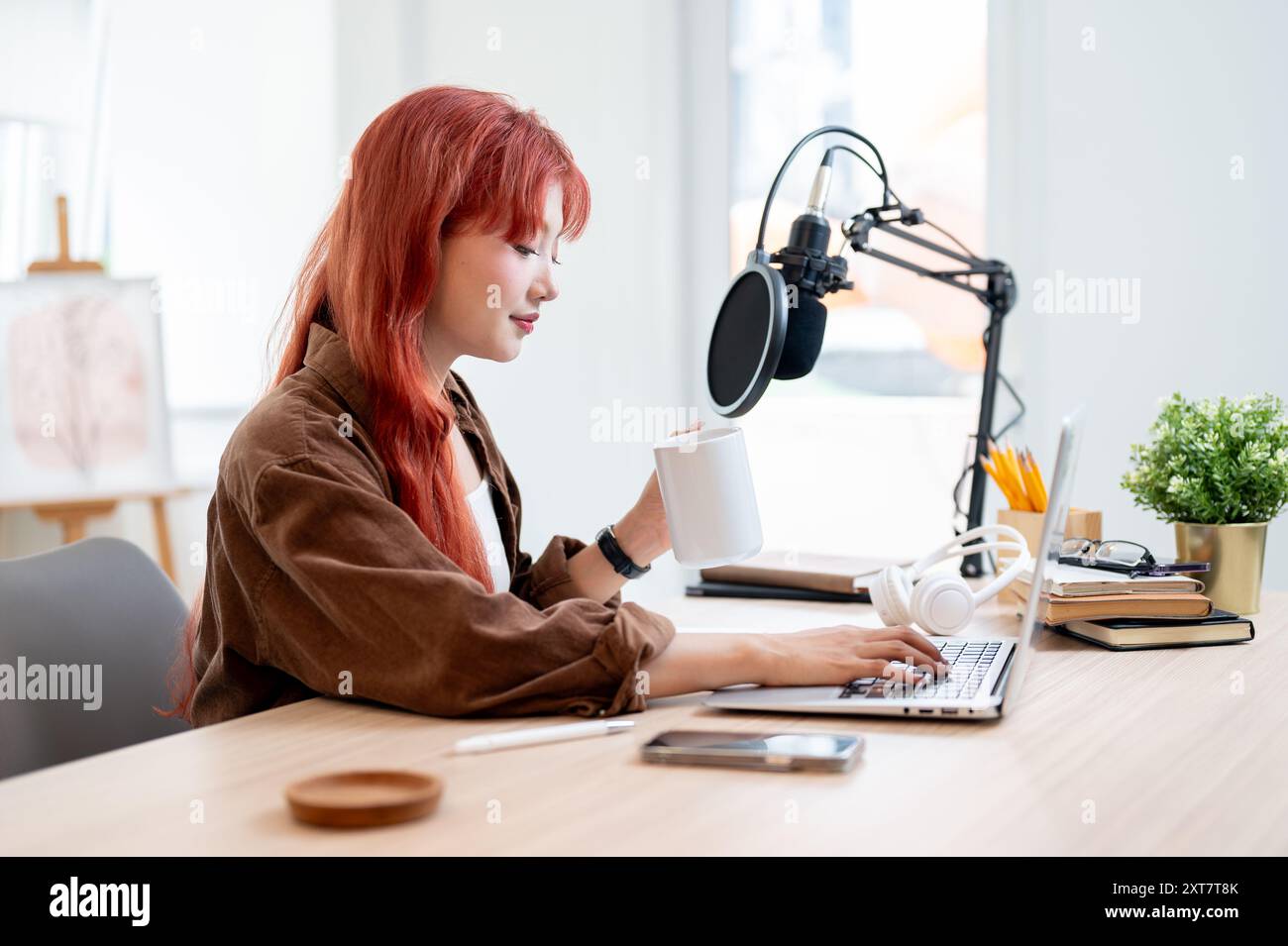 A confident and beautiful Asian female podcaster is working in her home ...