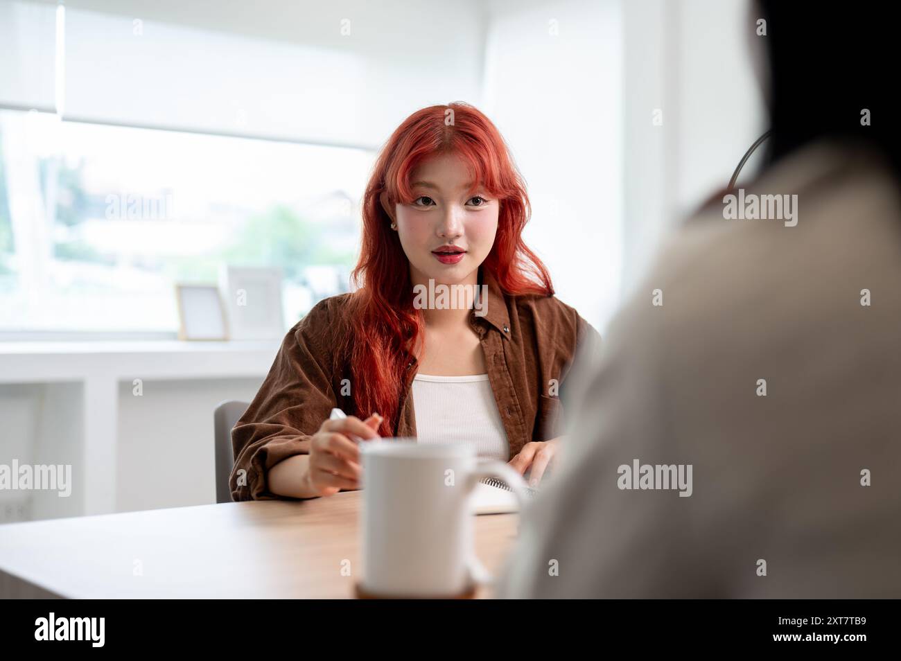 A beautiful Asian female podcaster with red curly hair is interviewing ...
