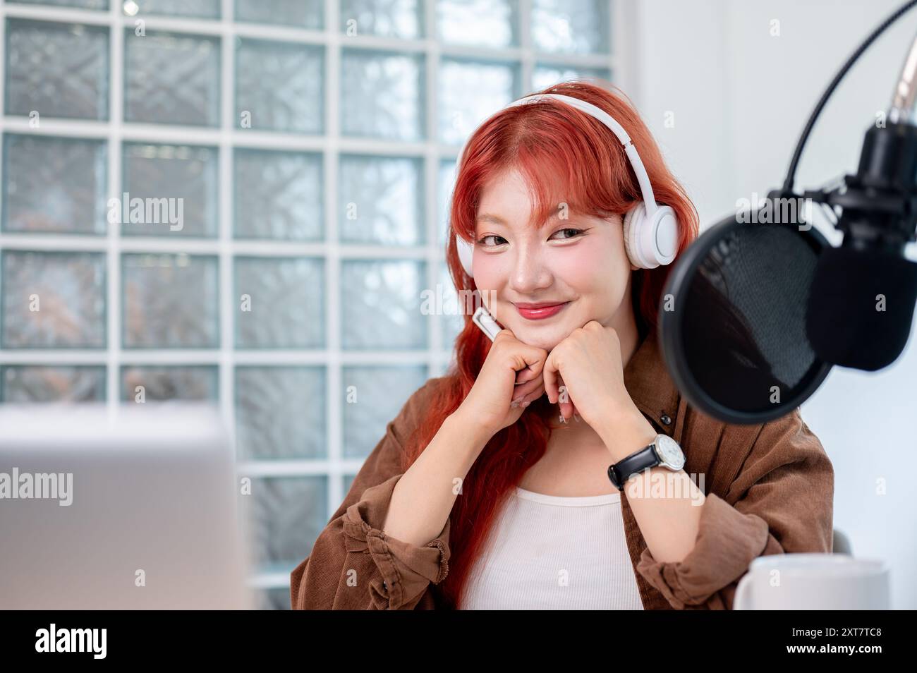 A beautiful and thoughtful Asian female podcaster with red curly hair ...