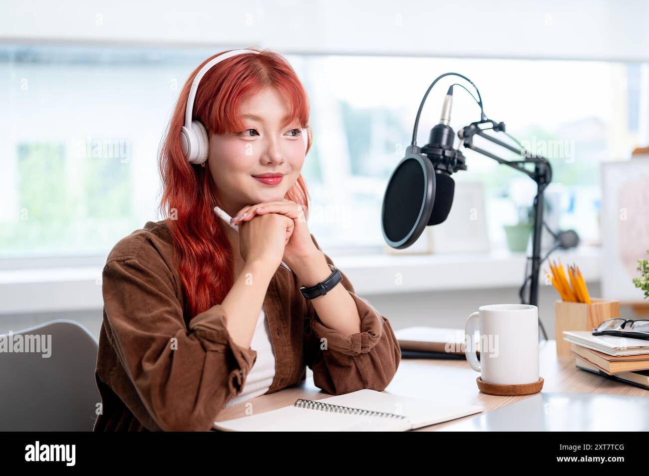 A beautiful and thoughtful Asian female podcaster with red curly hair ...