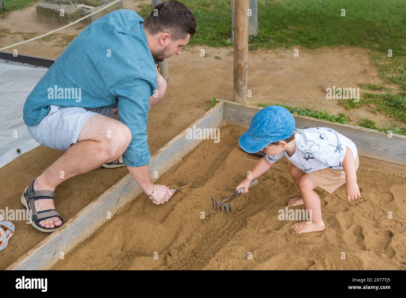 Dad and son in the sandbox at the archaeological park excavating with a ...