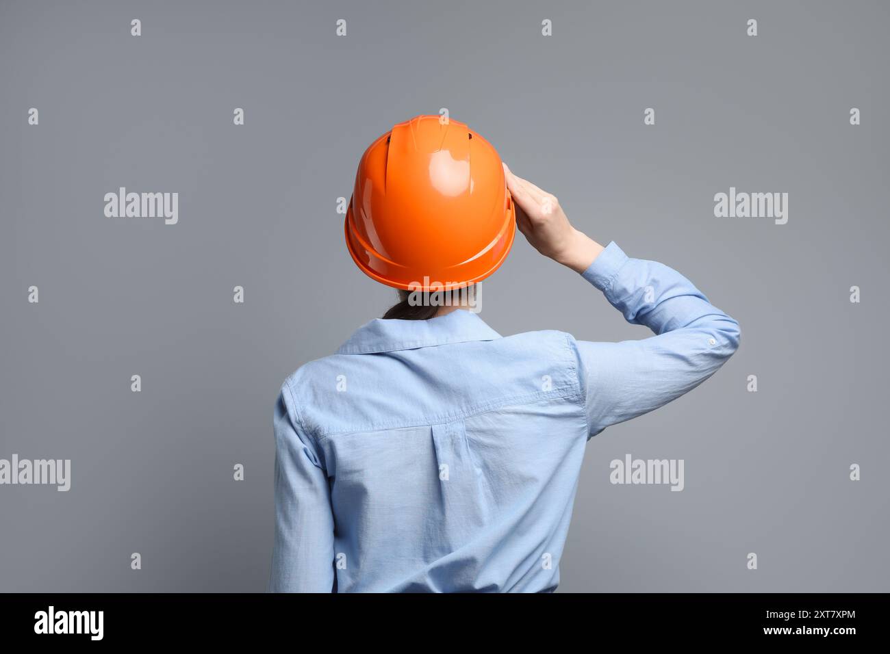 Engineer in hard hat on grey background, back view Stock Photo - Alamy