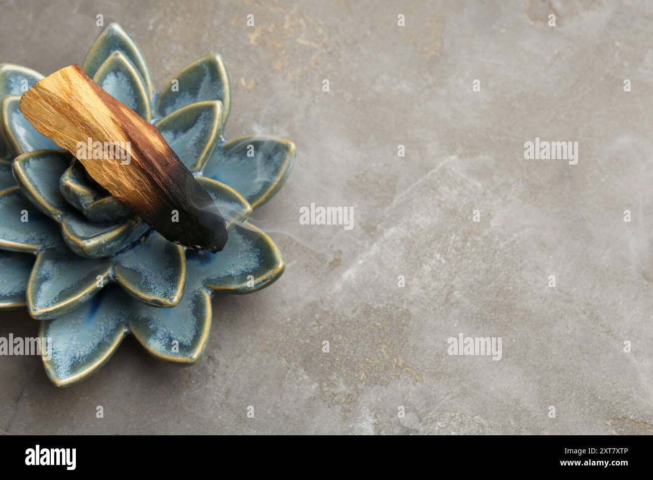 Smoldering Palo Santo stick and ceramic succulent on gray textured ...