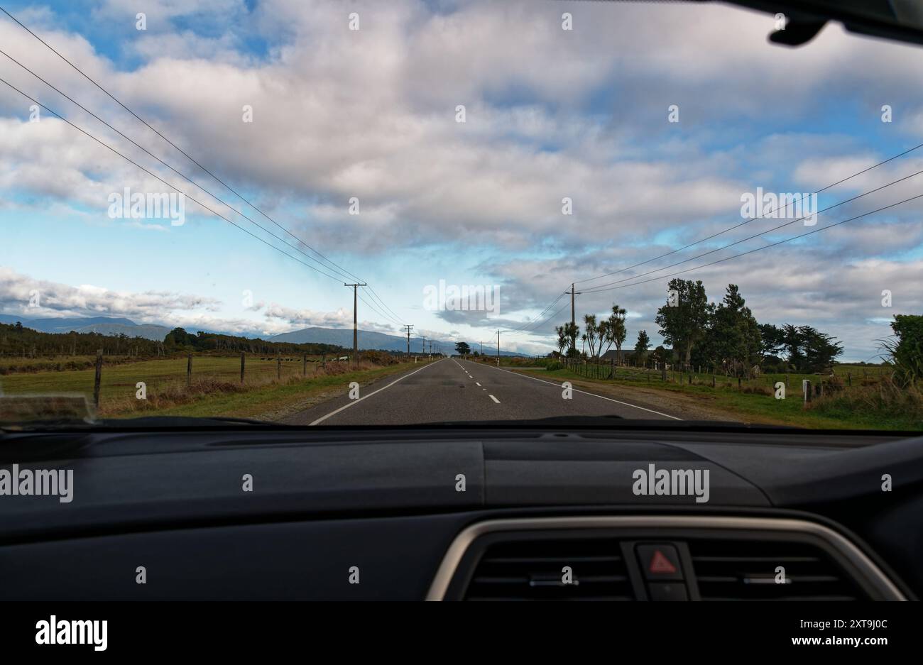 Power lines run overhead along the sides of a road in New Zealand. This ...