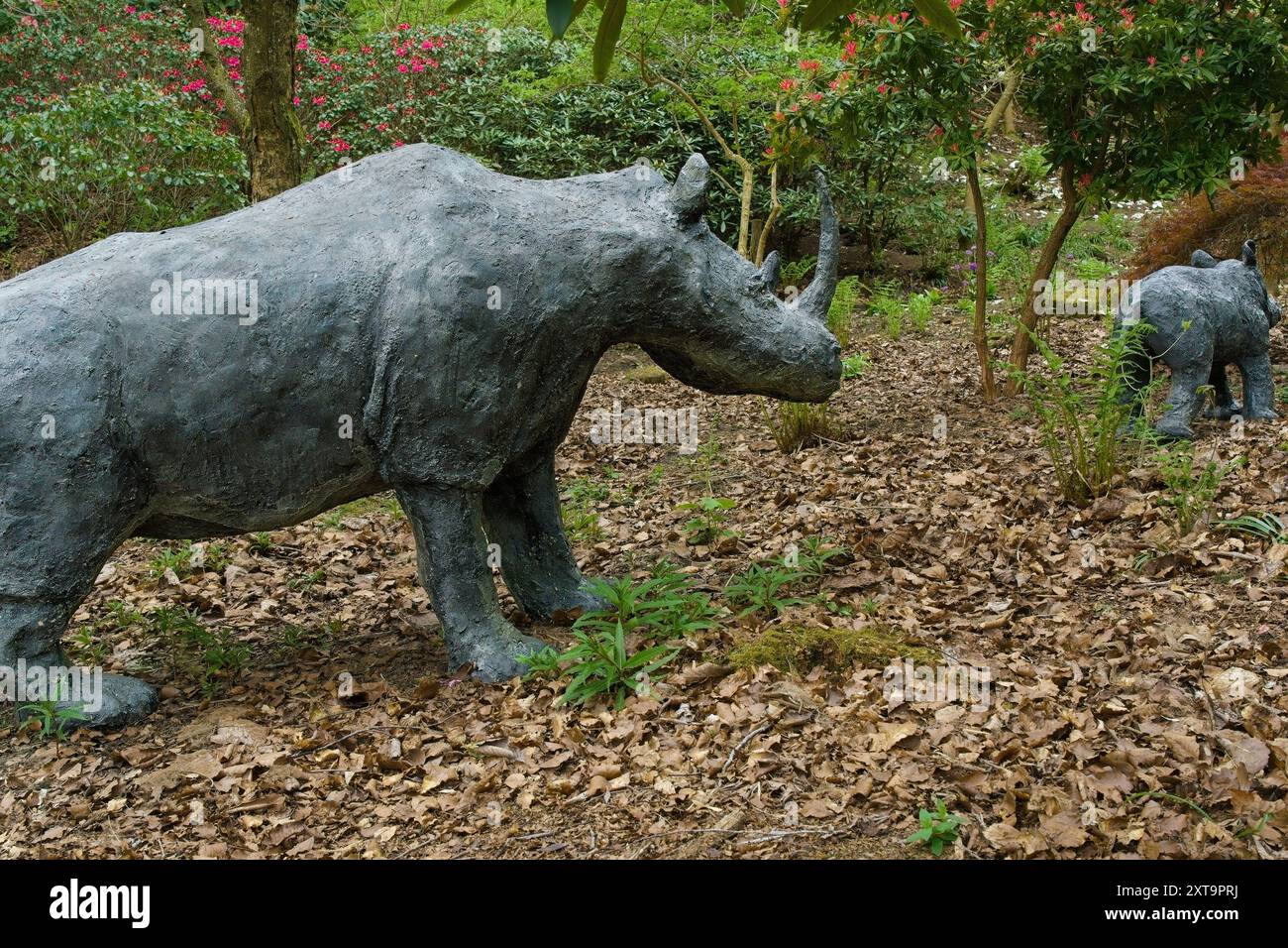 Garden sculptures of rhinos surrounded by trees, flowers, and green ...