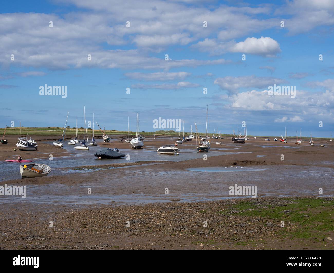 Boats at low tide in Summer at the coastal resort of Brancaster Staithe ...