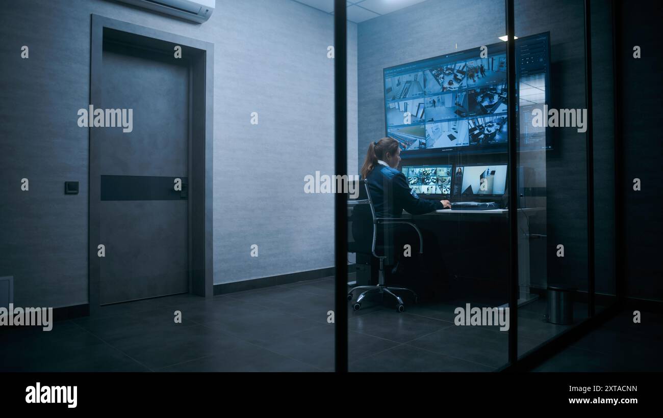 Female surveillance operator controls security cameras in modern monitoring center using ...