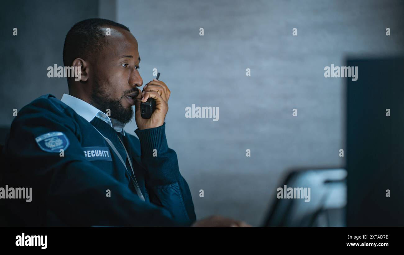 African American security officer or dispatch in uniform uses tablet ...