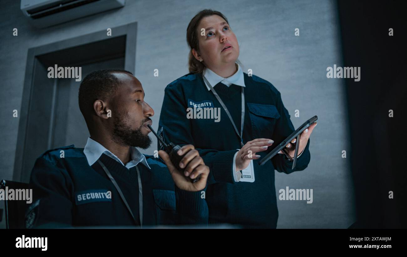 Female security officer stands and uses tablet computer. African ...