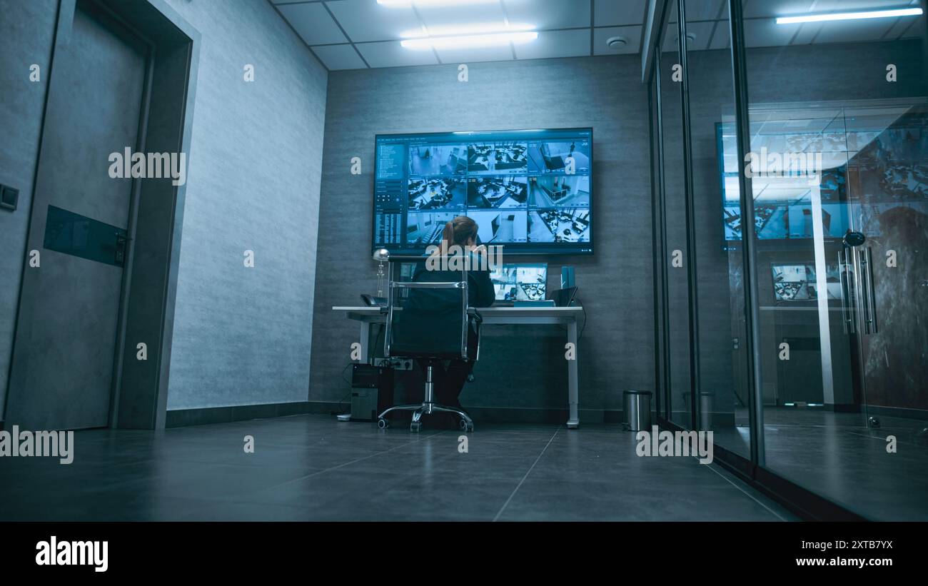 Back view of female CCTV operator watching security cameras on computer ...
