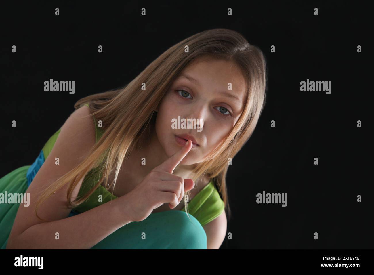 portrait of little girl with silence gesture on black background Stock ...