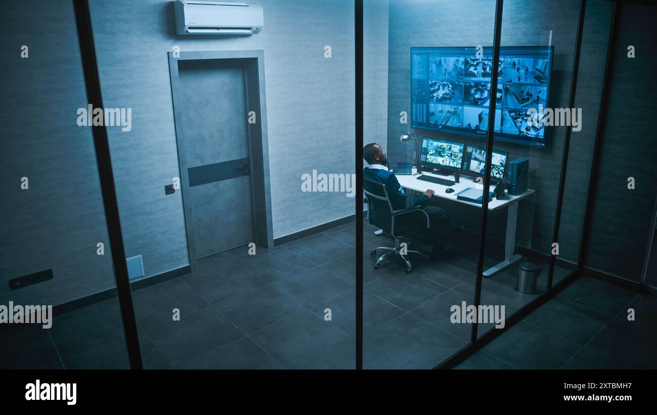 African American CCTV operator works on computer watching security ...