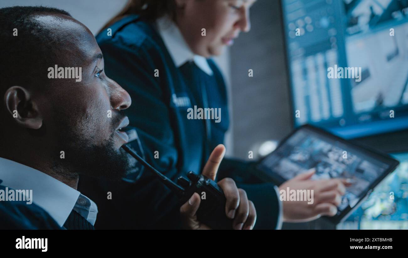 Multiethnic CCTV operators control security cameras on screens in ...