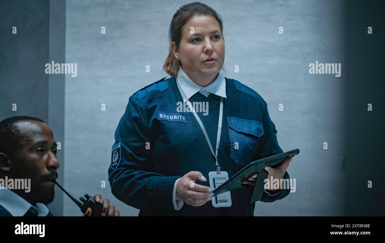 Female security worker talks with African American male colleague, uses ...
