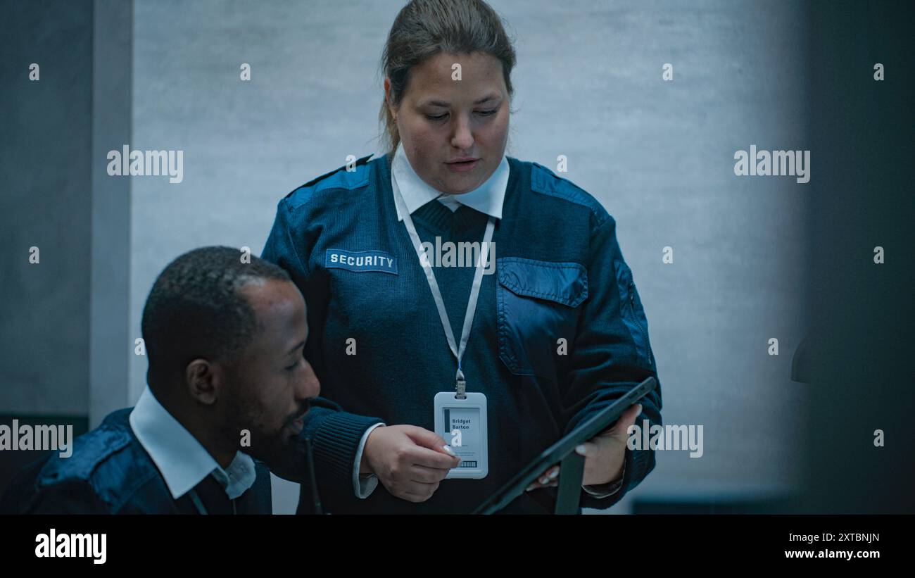 Female security worker talks with African American male colleague, uses ...