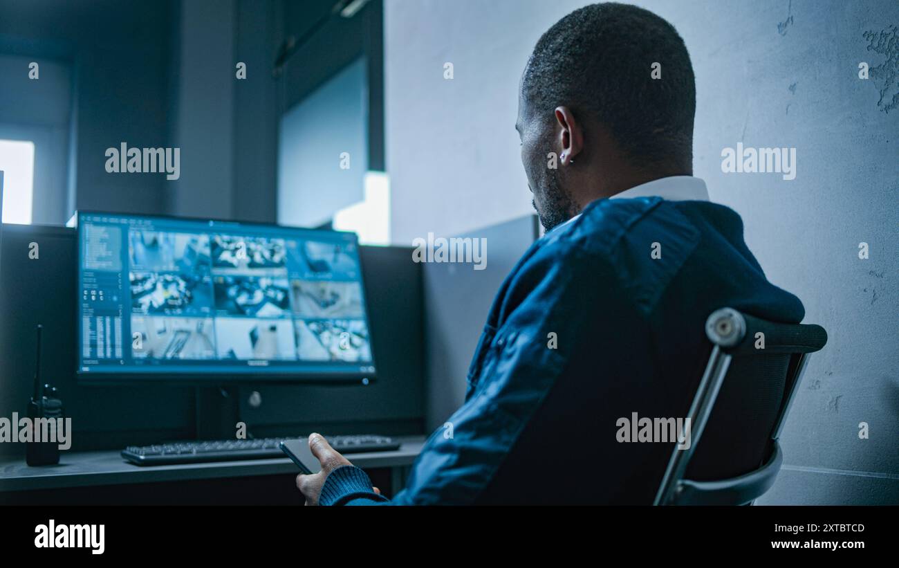 African American male security guard uses mobile phone sitting at the ...