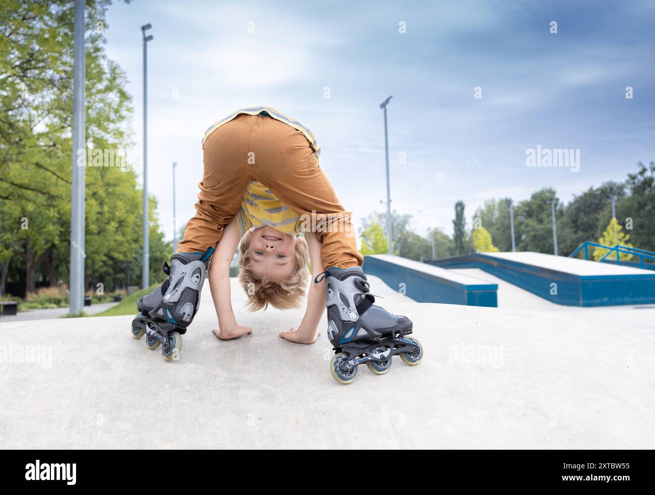 young cute boy stands on roller skates with his head down. learning to ...
