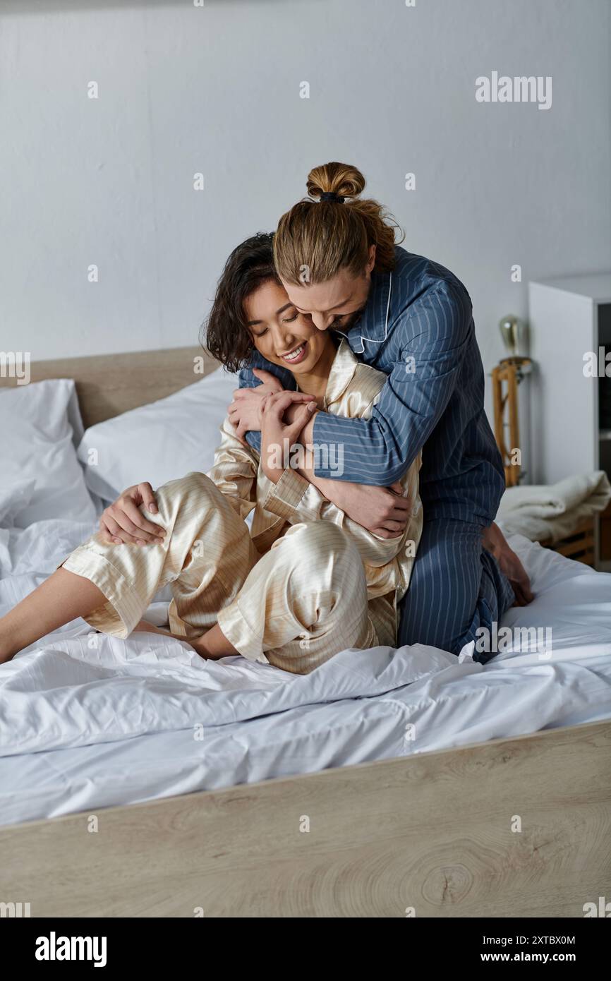 A loving couple hugs on a bed, expressing their affection for each ...
