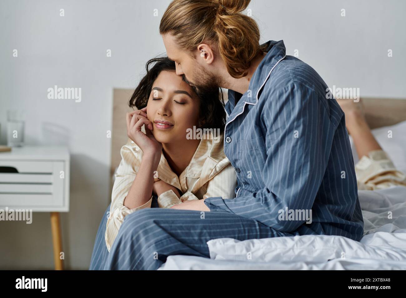 A loving couple in pajamas share a tender morning kiss Stock Photo - Alamy