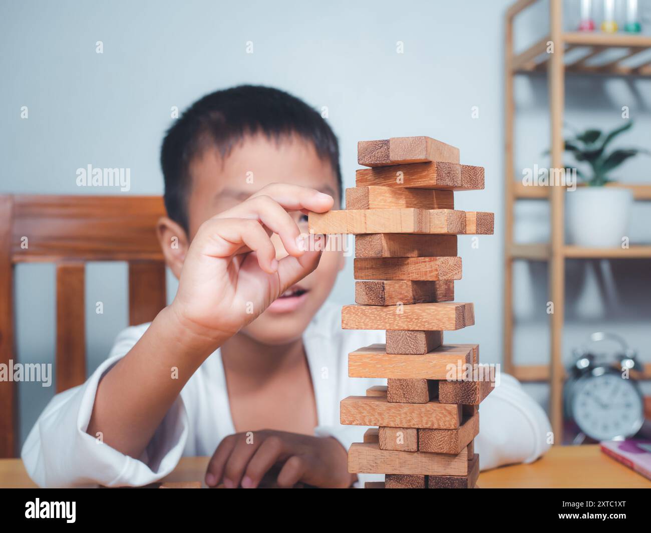 Cheerful Asian boy playing with wooden building blocks Jenga, Having ...