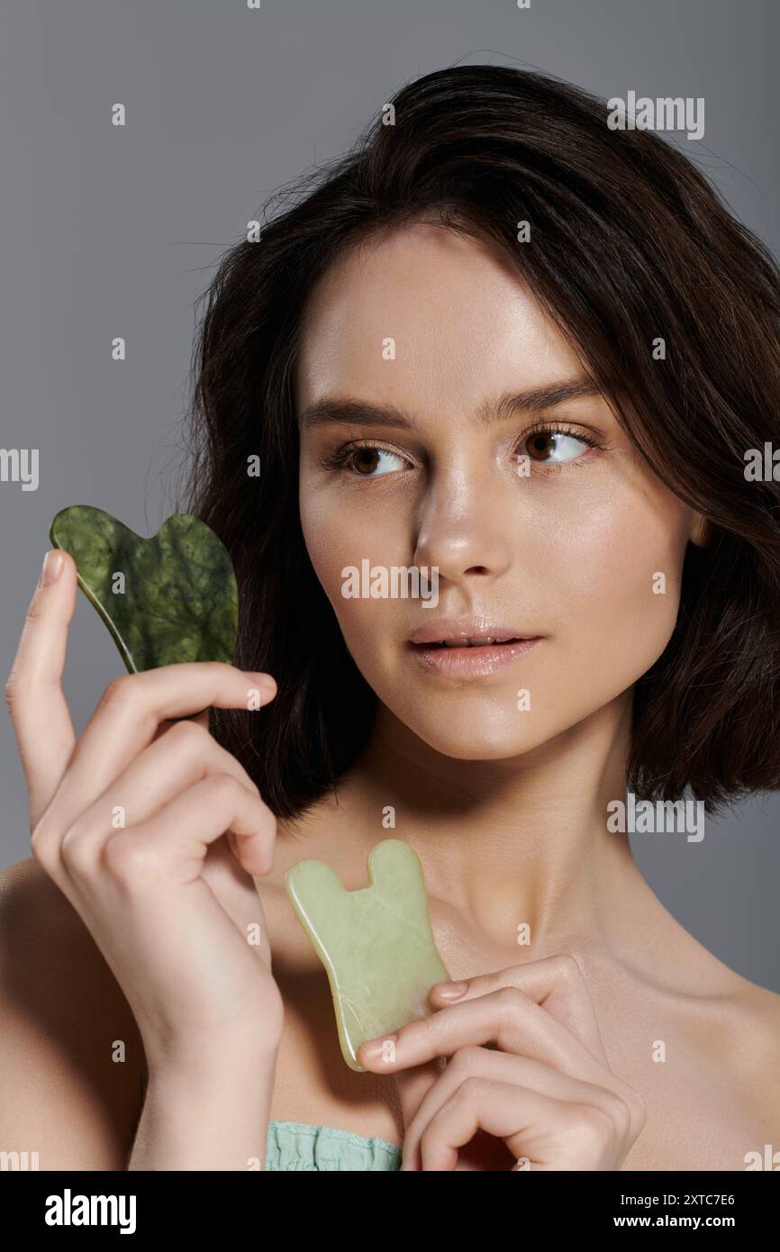 A woman holds two jade gua sha tools in her hands Stock Photo - Alamy