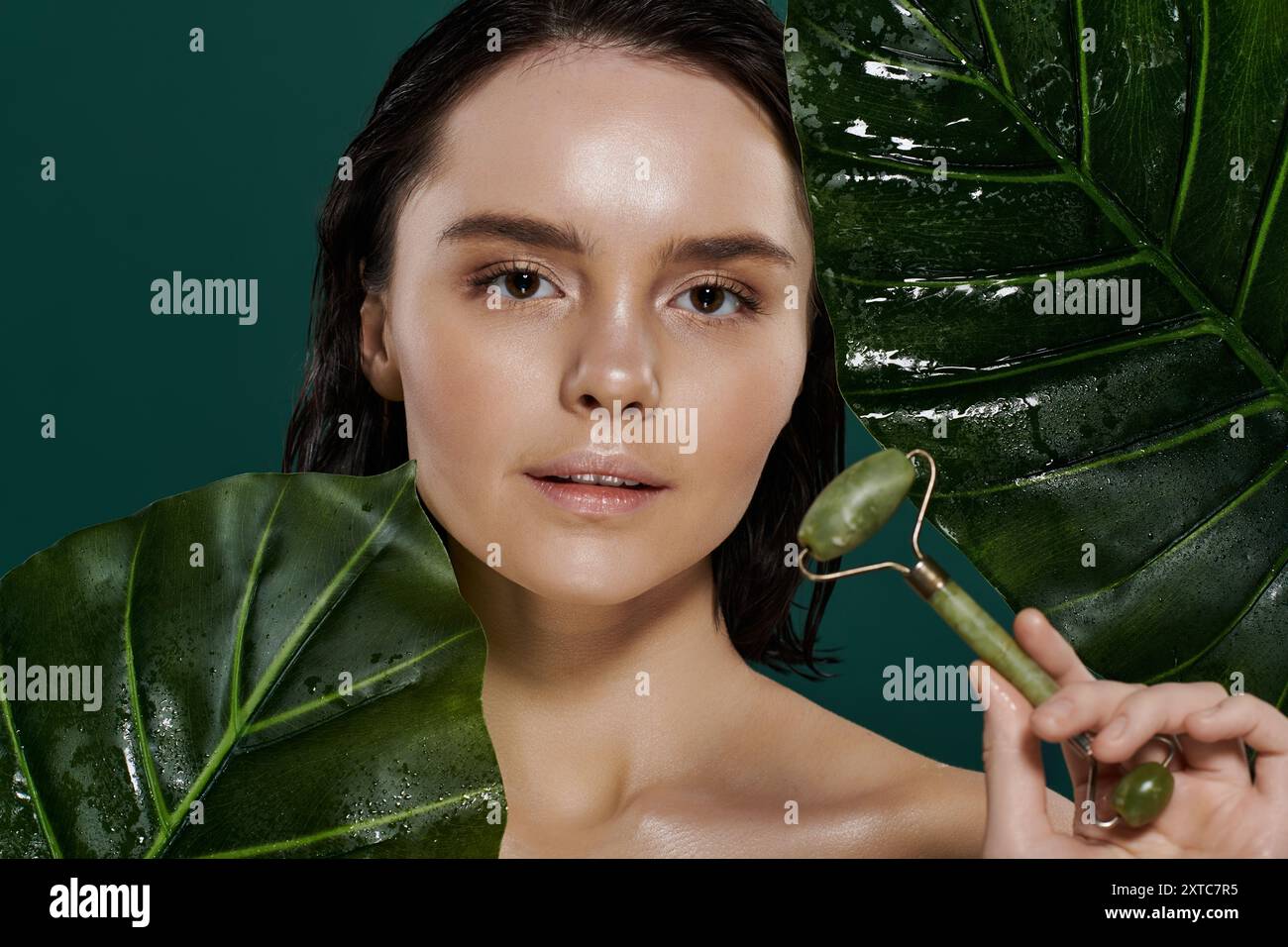 A beautiful woman poses with a jade roller, surrounded by lush green ...