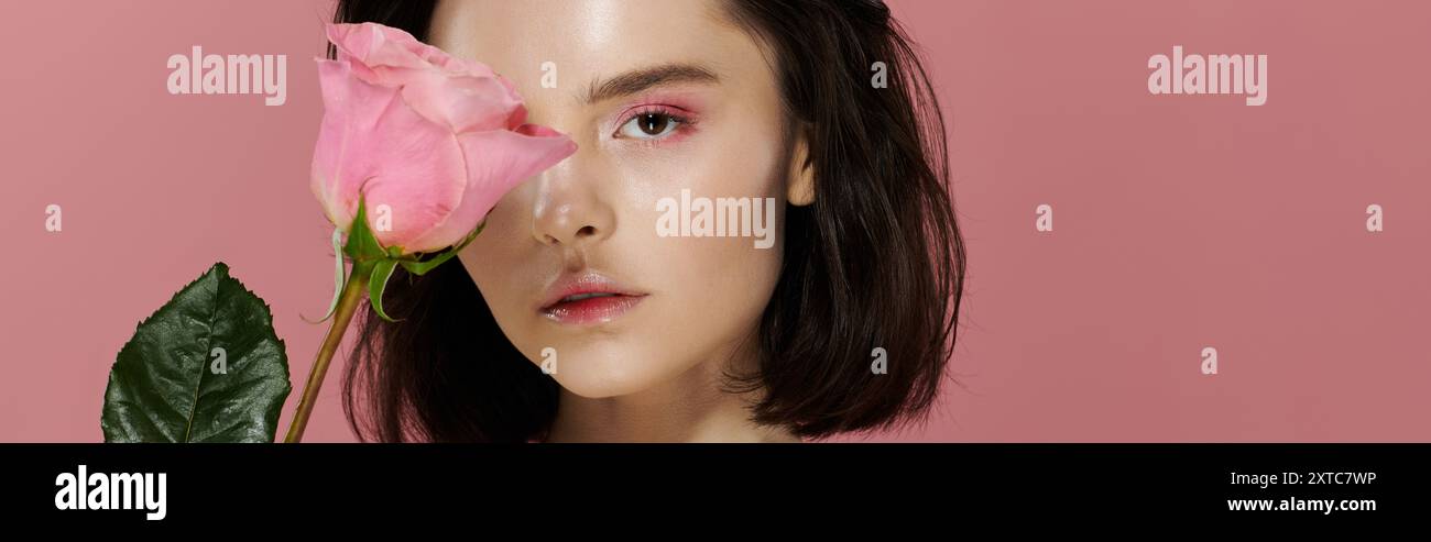 A woman with dark hair poses in front of a pink backdrop, a single pink ...