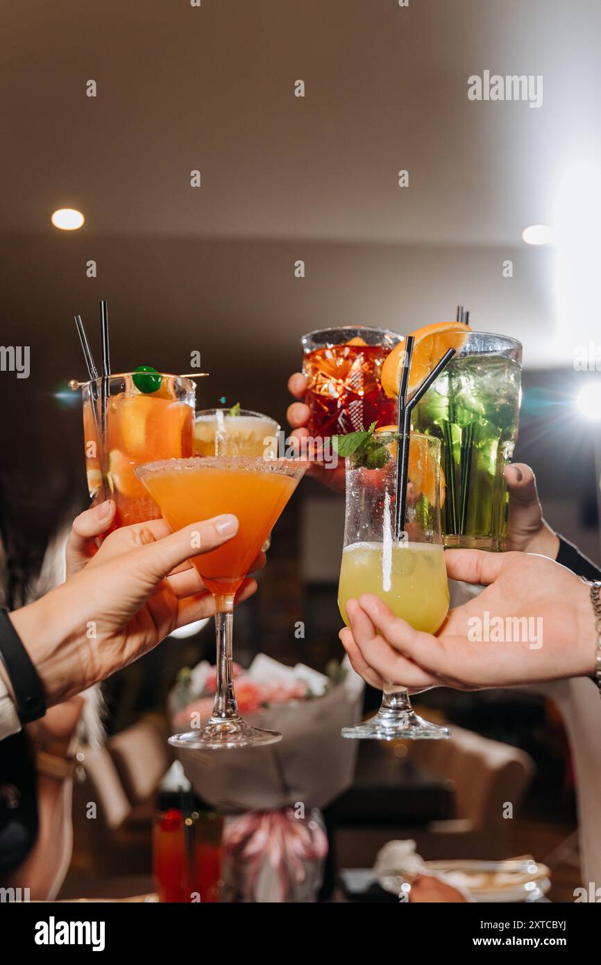 Group of friends toasting with cocktails in a vibrant bar setting ...
