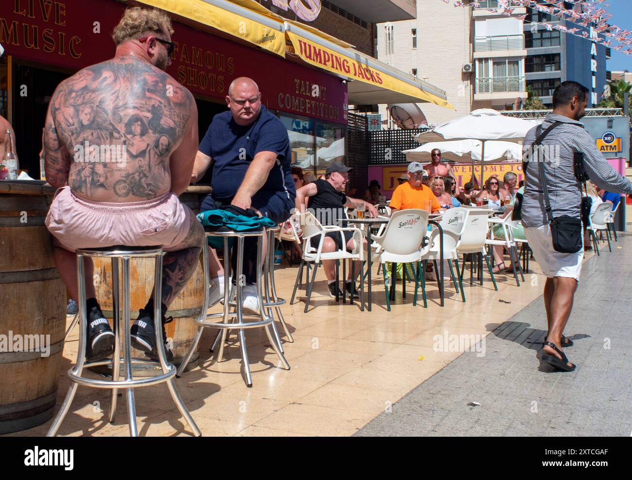 tattooed Englishmen sit in front of English bar and watch dark-skinned ...