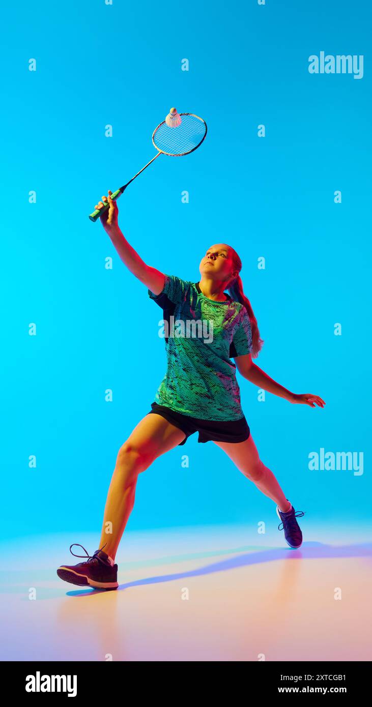 Young woman, badminton athlete leaping in motion to hit shuttlecock ...