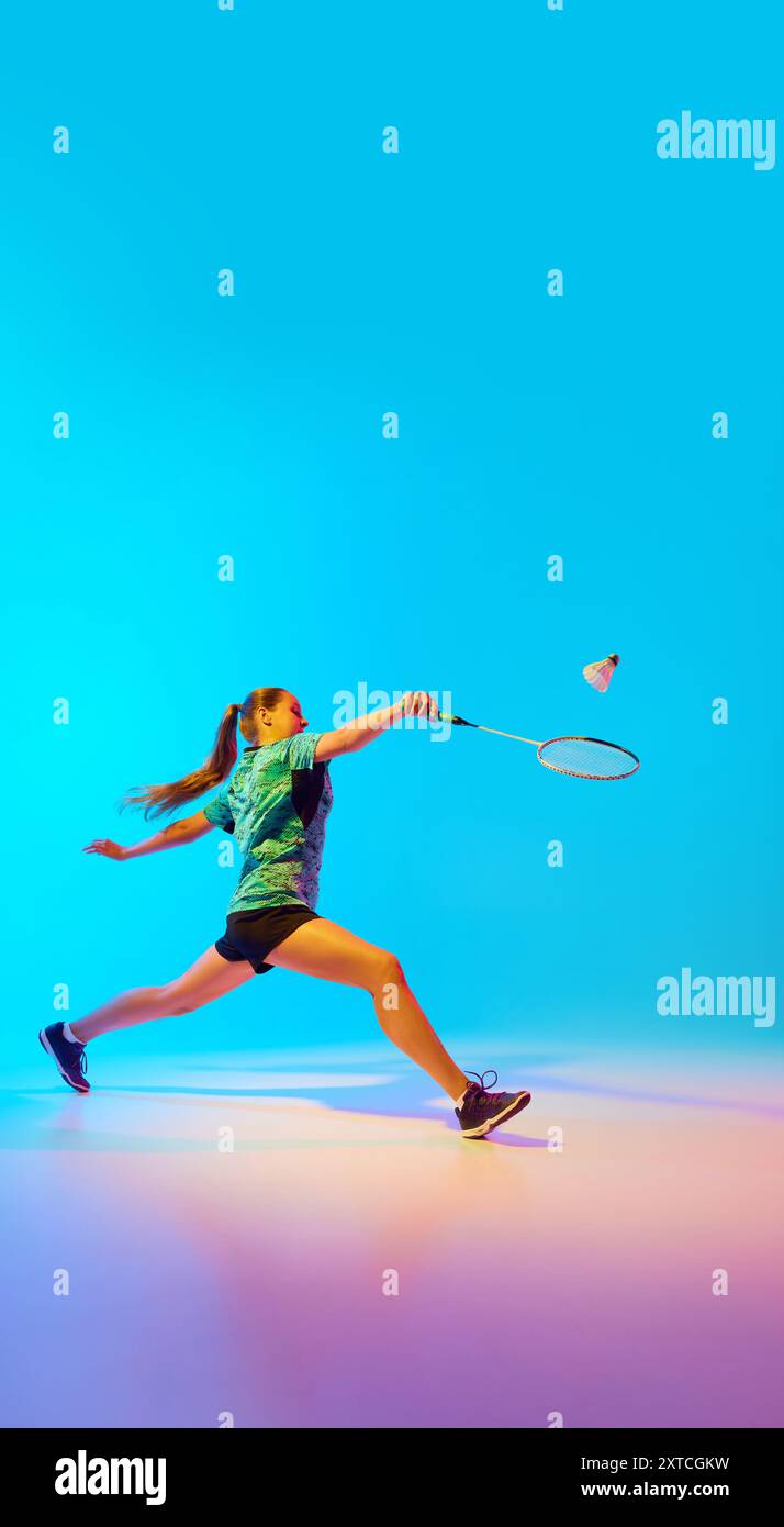 Young woman, badminton athlete leaping in motion to hit shuttlecock ...