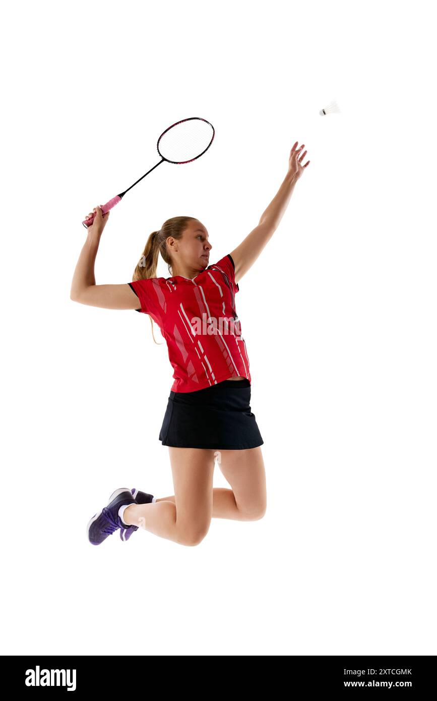 Young girl, badminton athlete, jumping in mid-air to hit shuttlecock ...