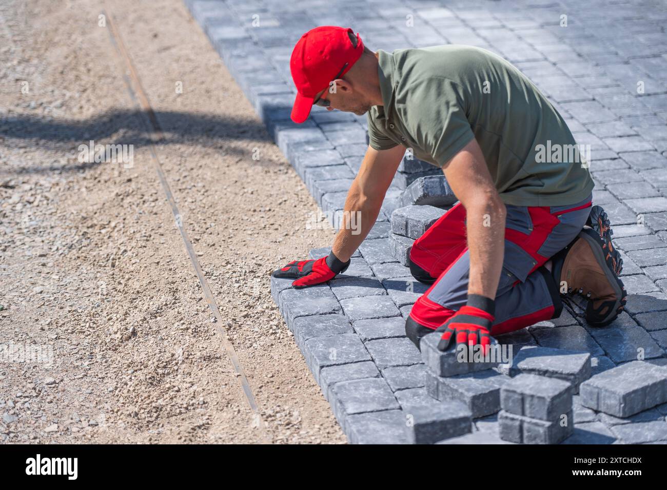 A construction worker laying paving stones on a pathway at a ...