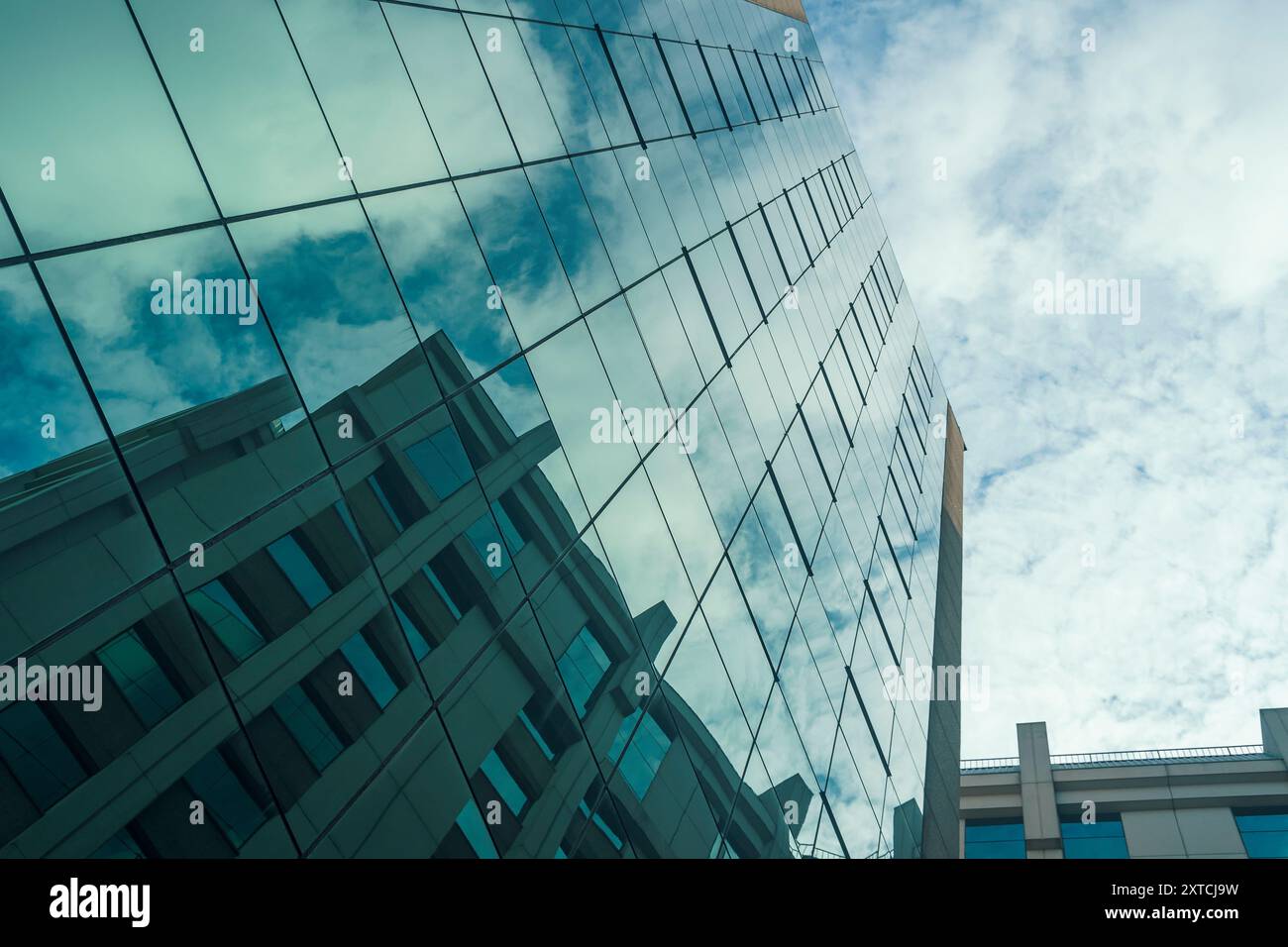 Glass facade of modern building reflecting another building with blue ...
