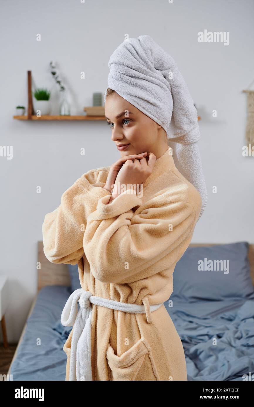 A young woman relaxes in her home, wearing a plush robe and a towel ...