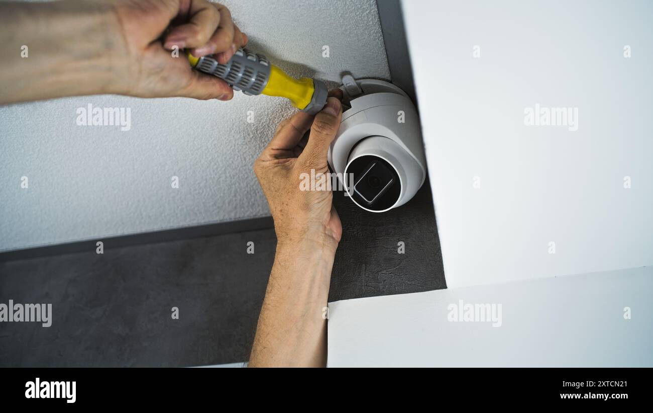 Professional male technician or installer attaches security camera to ...