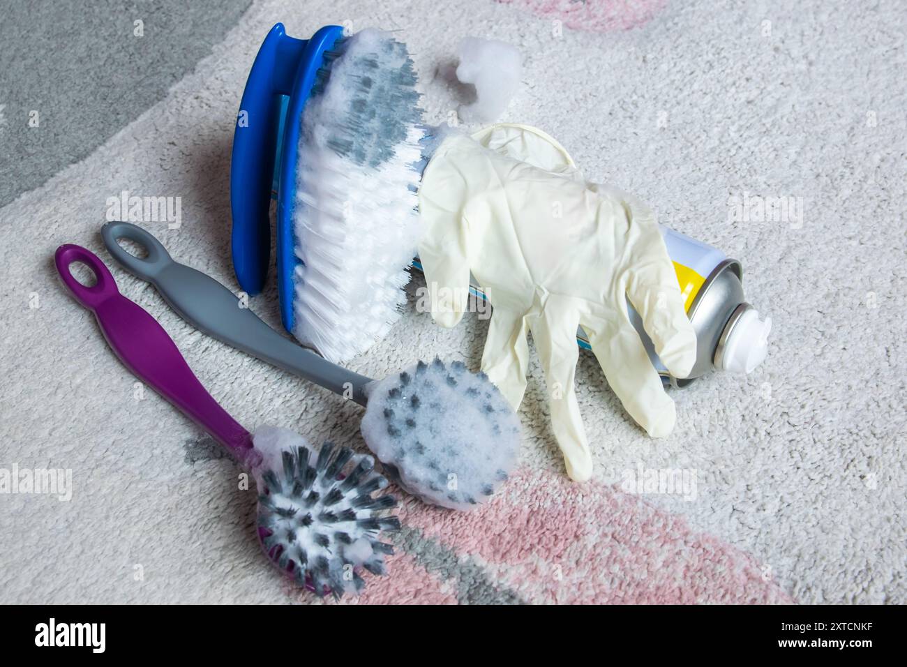 Rubber glove, brushes and bottle with cleaning fluid on the floor ...