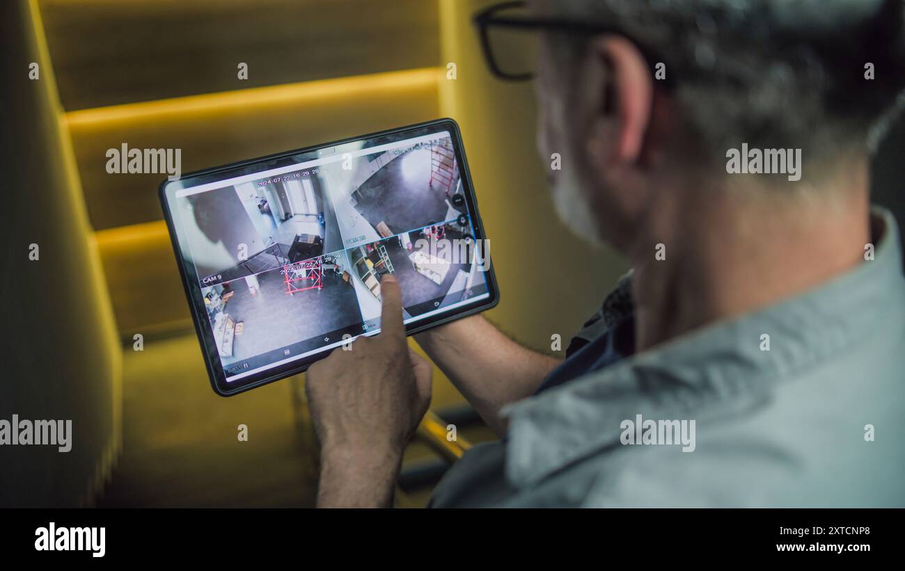 Male mature technician watches and controls CCTV cameras in modern ...